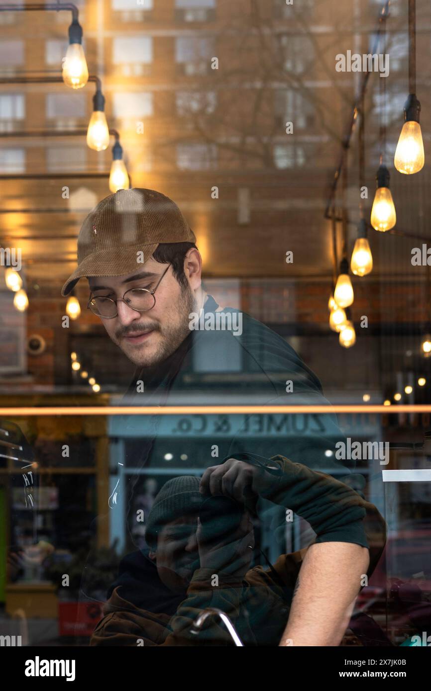 Man inside coffee shop with photographer's reflection in the window ...