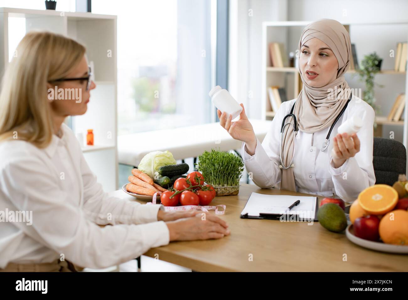 Muslim doctor in hijab receives female patient in modern clinic Stock ...