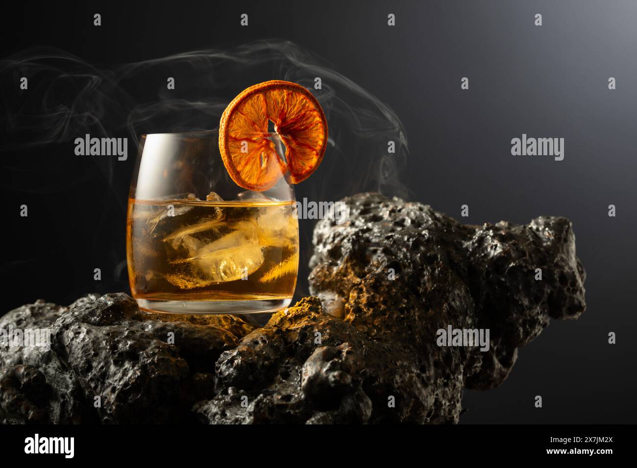 Smoked old fashioned rum cocktail with ice and dried orange slice on a ...