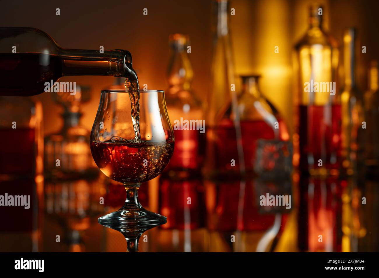 Pouring brandy from a bottle into a glass. Snifter of brandy on a black ...