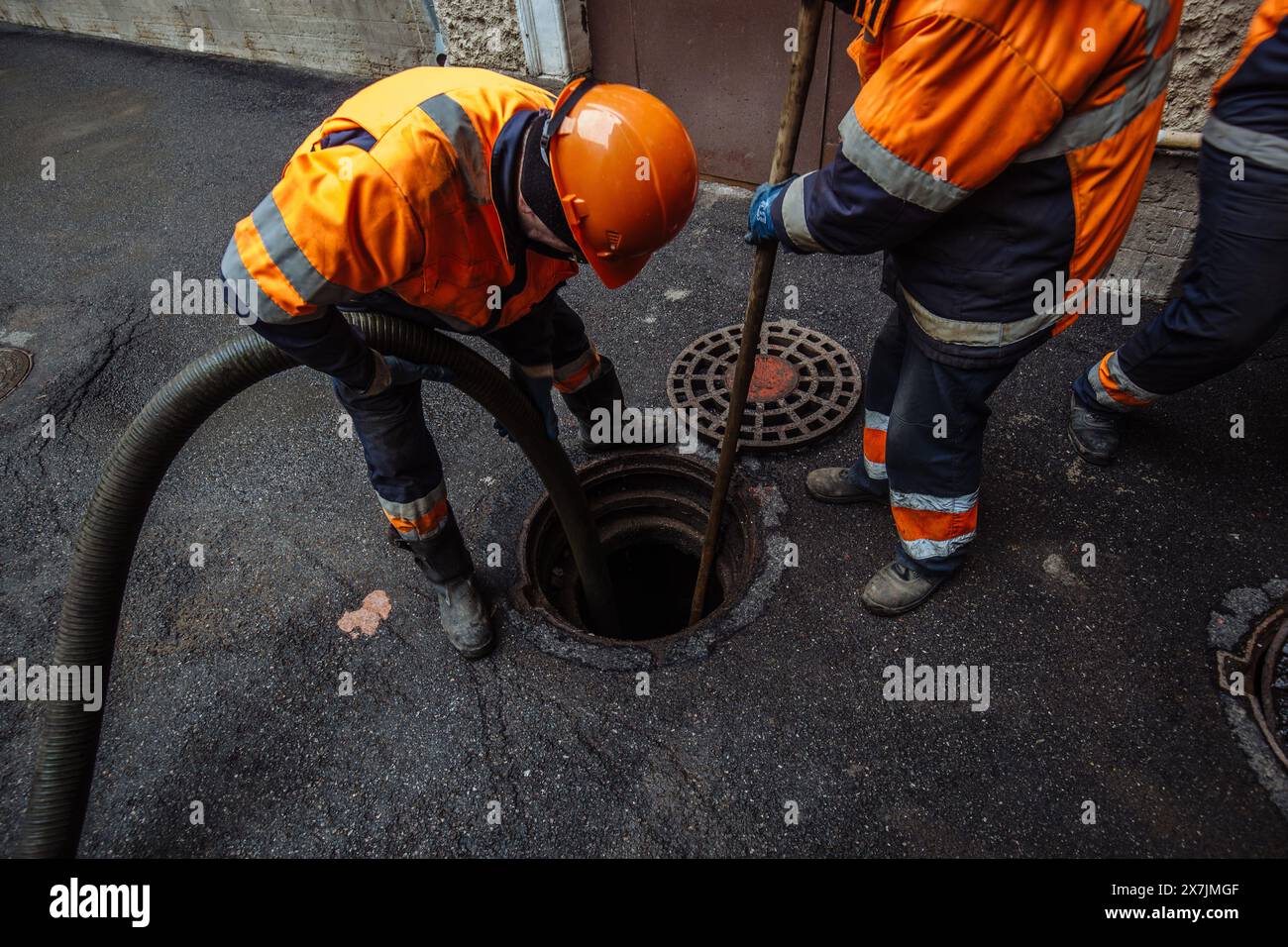 Sewer workers cleaning manhole and unblocking sewers the street ...