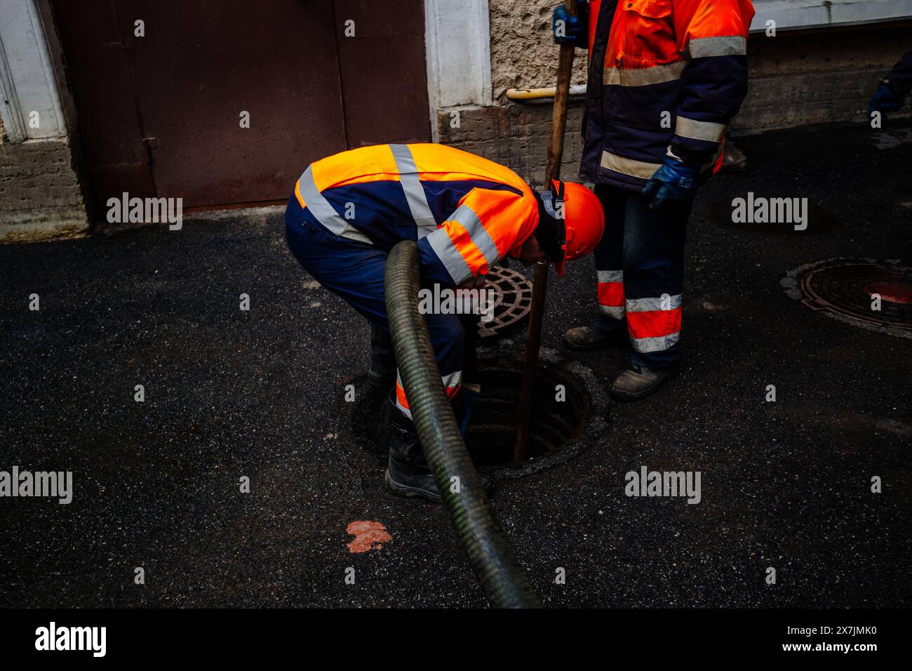 Sewer workers cleaning manhole and unblocking sewers the street ...