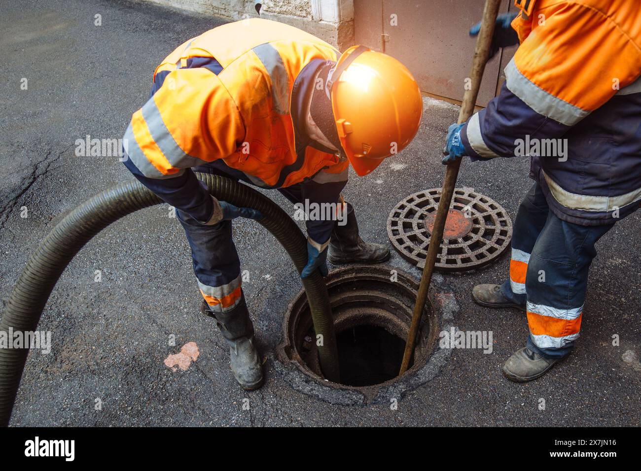 Sewer workers cleaning manhole and unblocking sewers the street ...