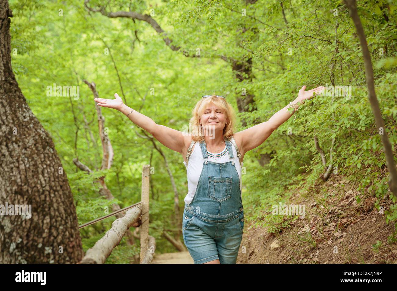 Middle aged woman walking along forest path with backpack Stock Photo ...
