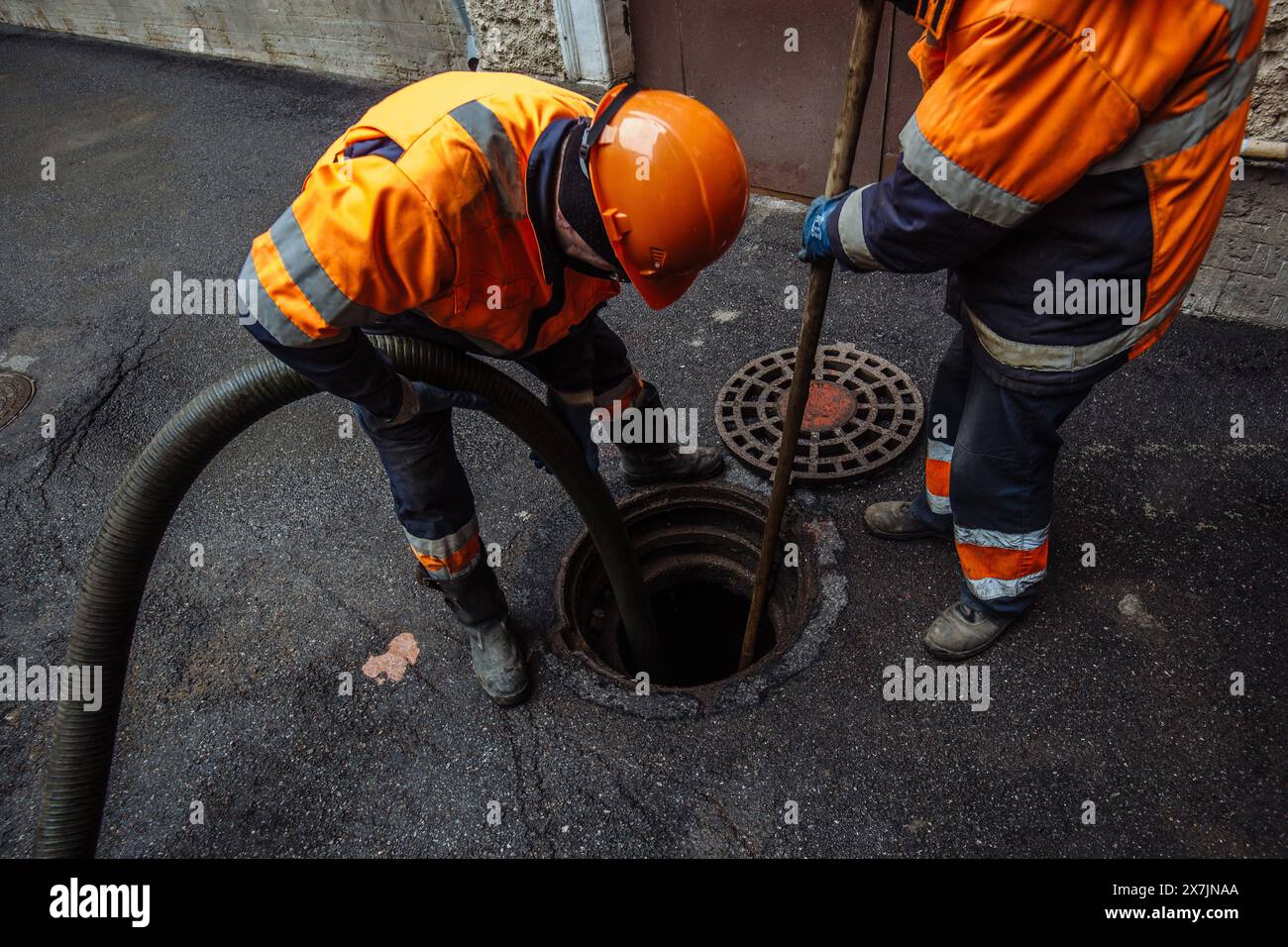 Sewer workers cleaning manhole and unblocking sewers the street ...