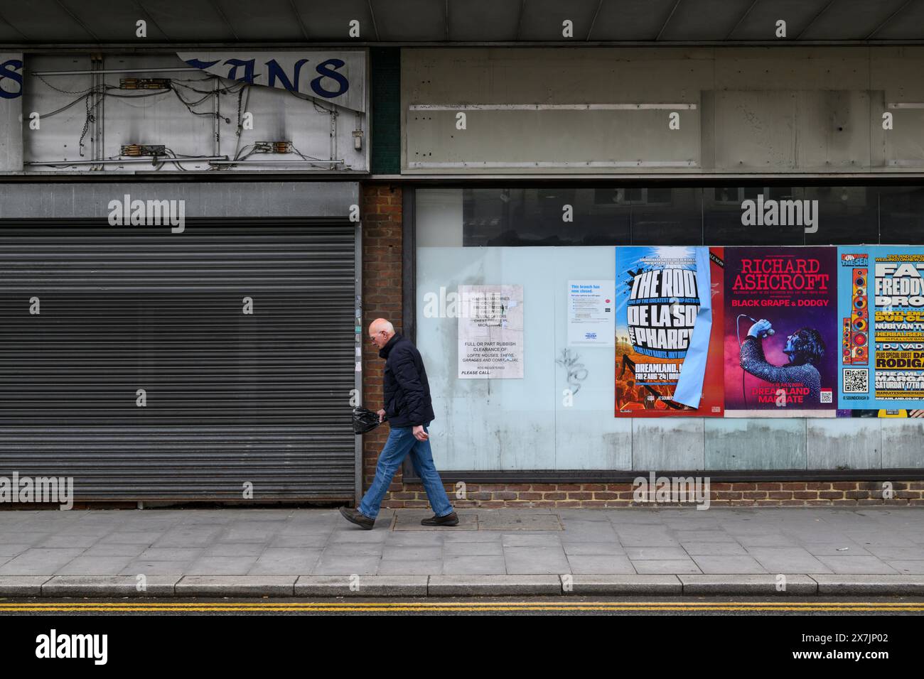 A man walking past a closed-down shop, High Street, Strood, Kent, UK ...