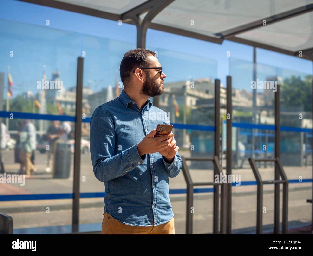 man using his phone while waiting at the bus stop Stock Photo - Alamy