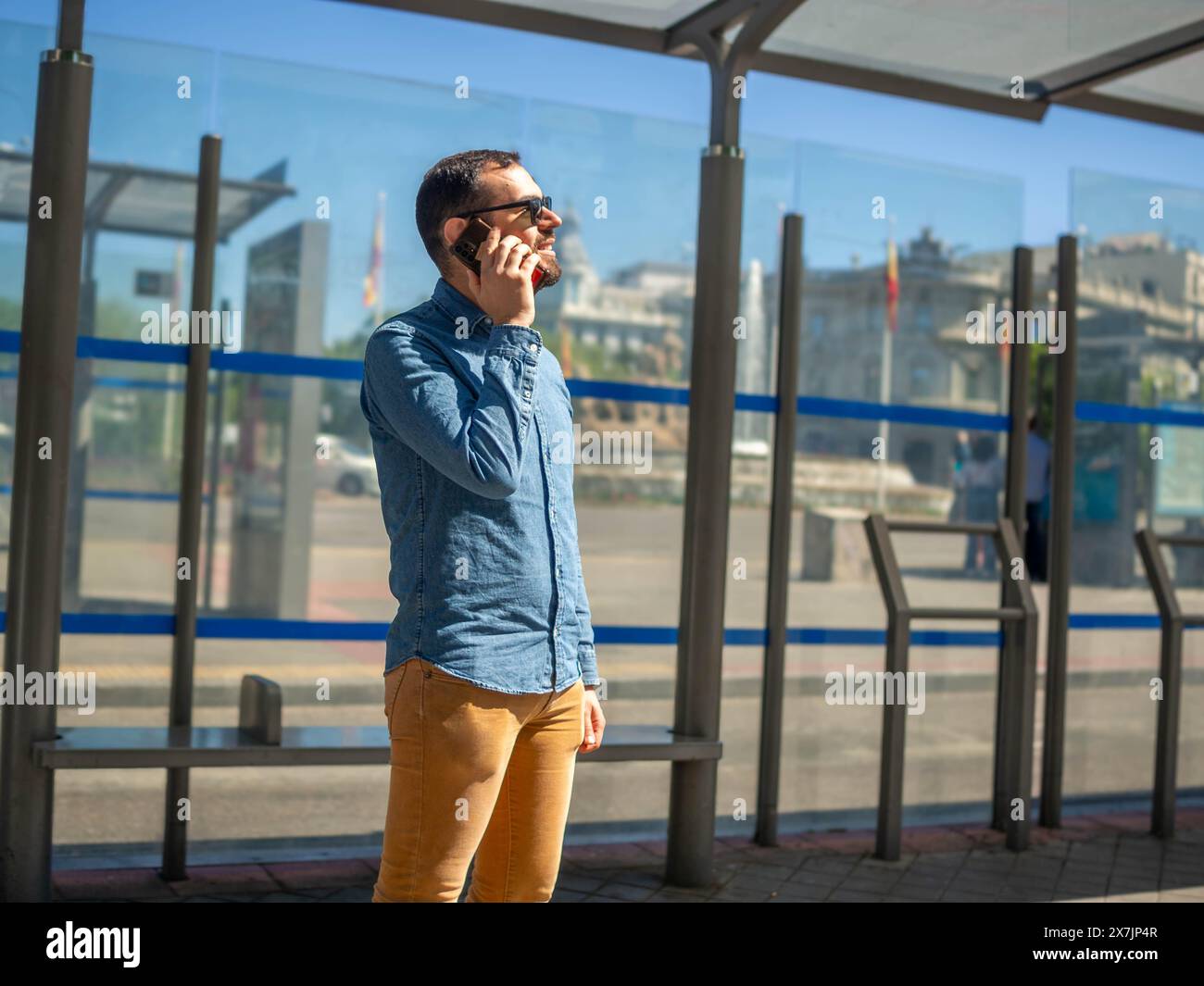 man using his phone while waiting at the bus stop Stock Photo - Alamy