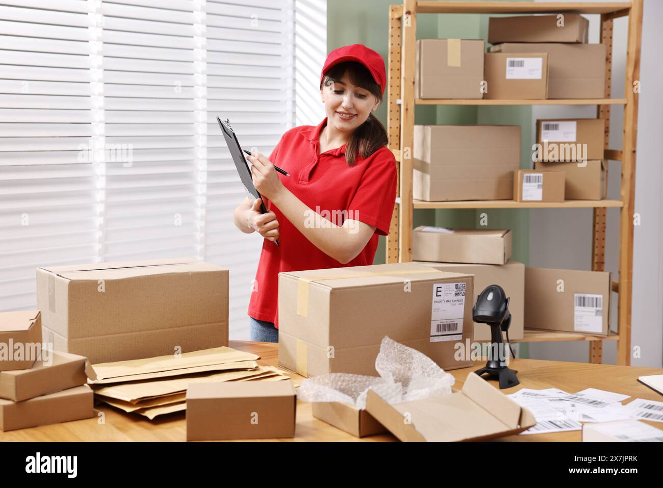 Parcel packing. Post office worker with clipboard at wooden table indoors Stock Photo - Alamy