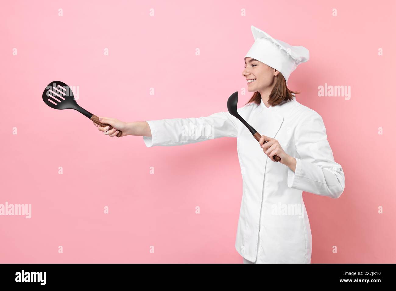 Professional chef with skimmer and ladle having fun on pink background ...