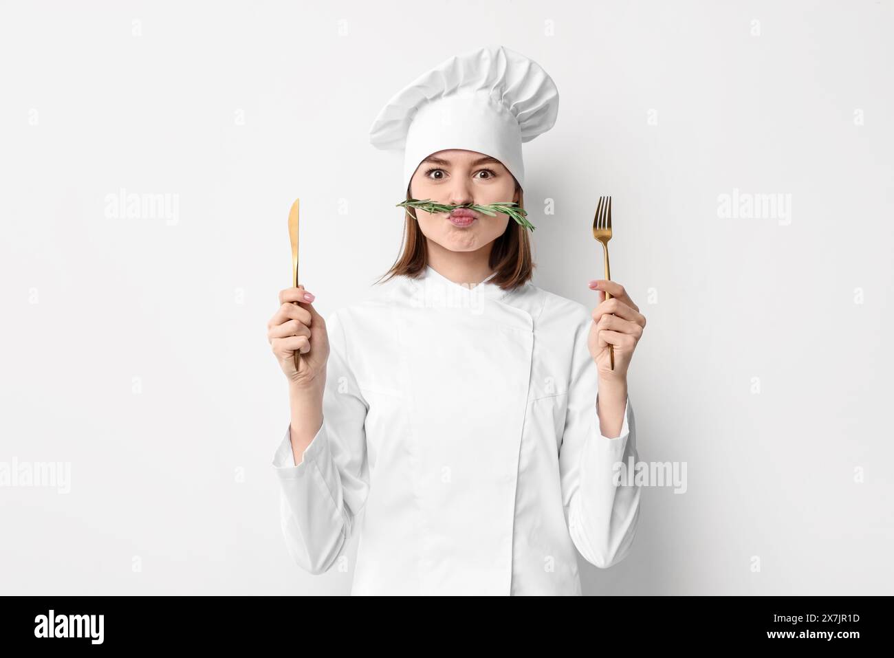 Professional chef with rosemary and cutlery having fun on light ...