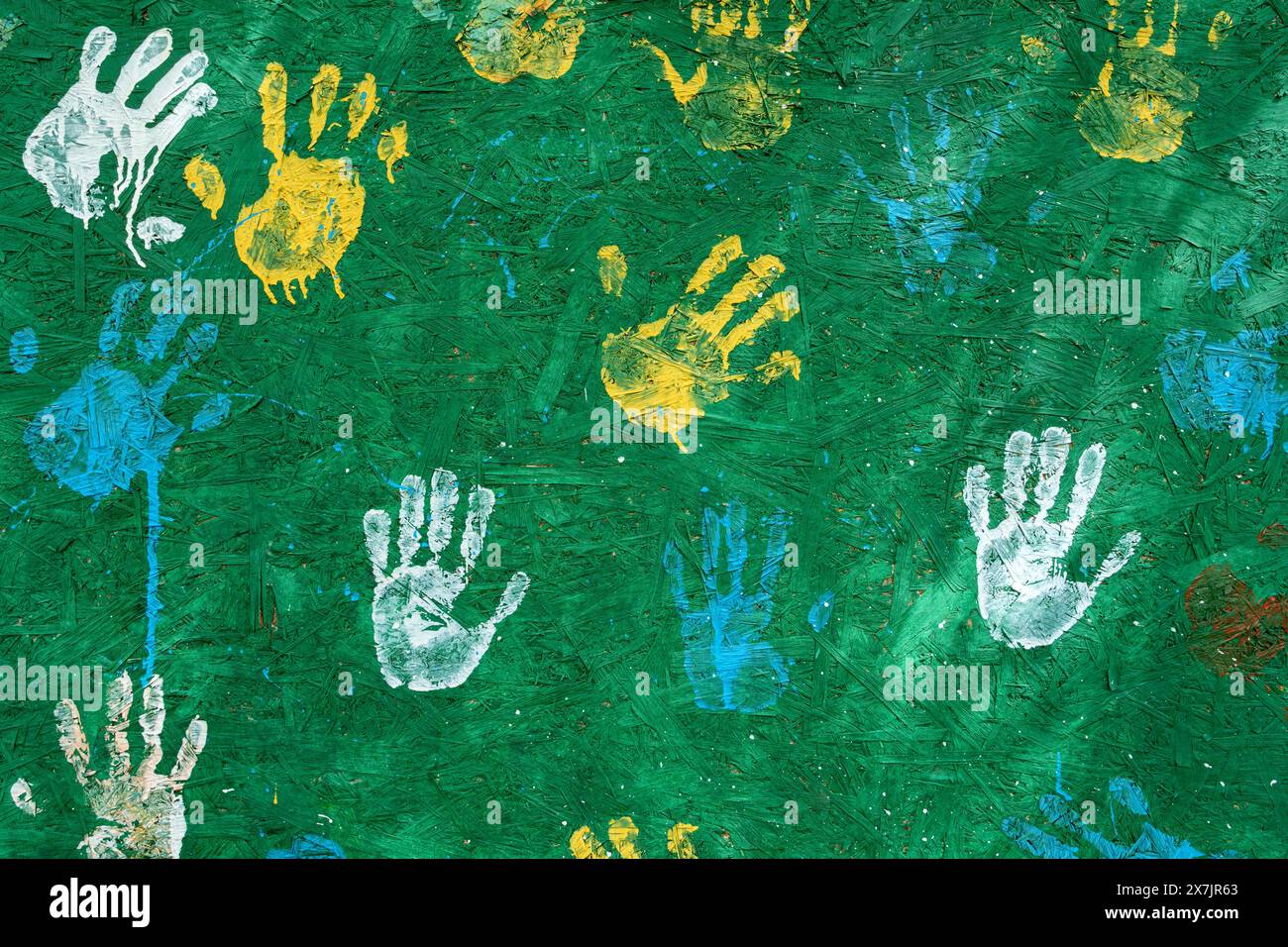 Various colorful handprints are painted on a textured green wall ...