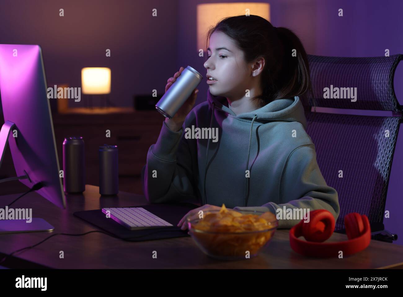 Girl with energy drink playing computer game at table in room Stock ...