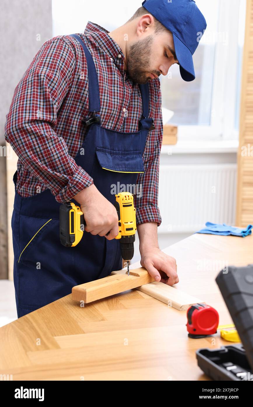 Young worker using electric drill at table in workshop Stock Photo - Alamy