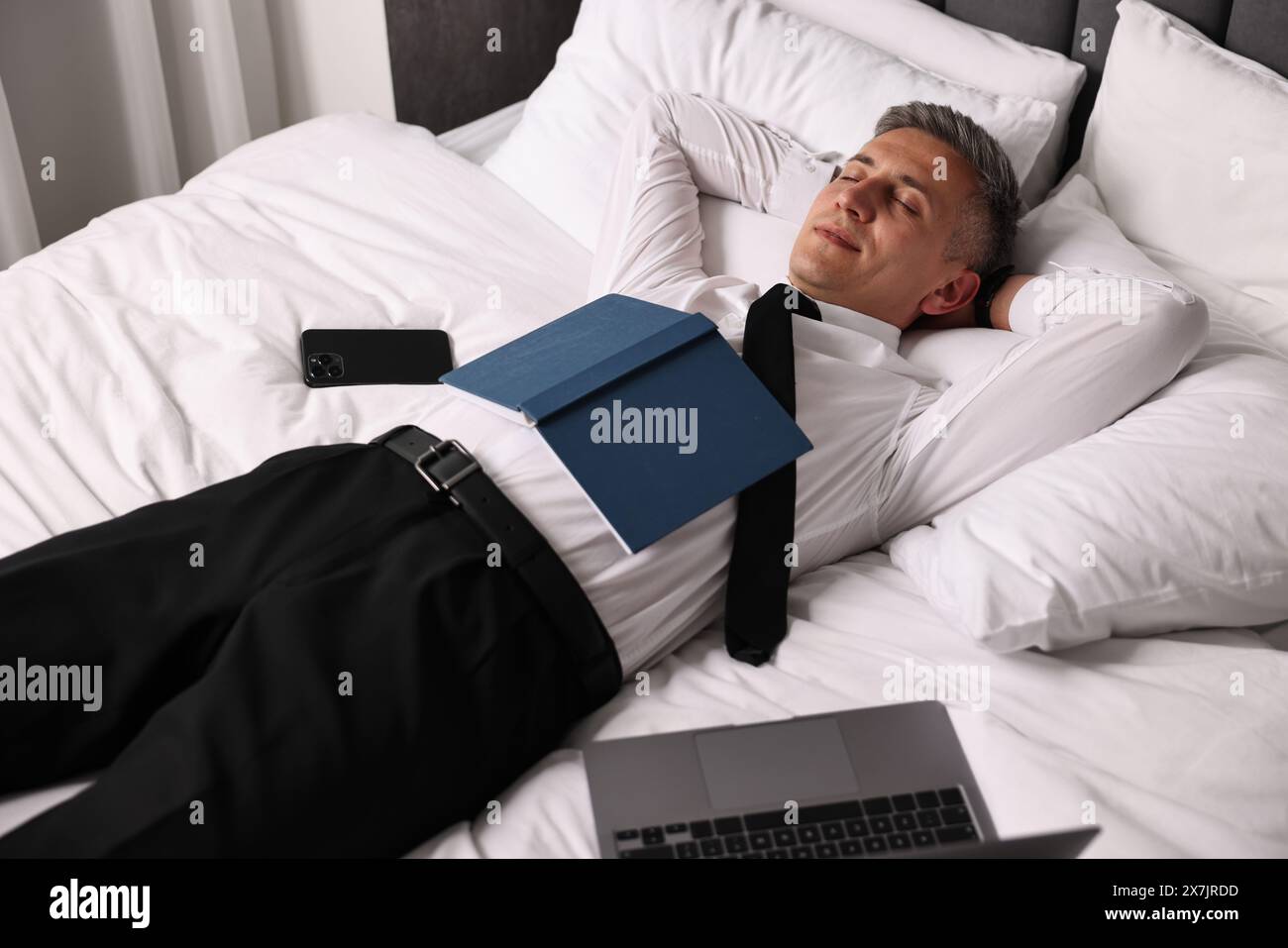 Businessman in office clothes sleeping on bed indoors Stock Photo - Alamy