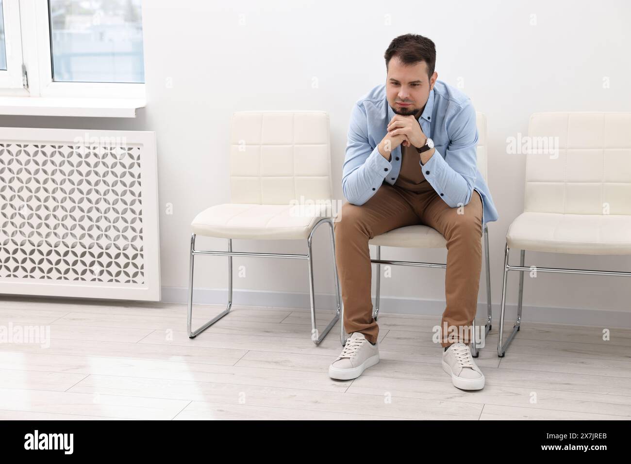 Man sitting on chair and waiting for appointment indoors Stock Photo ...