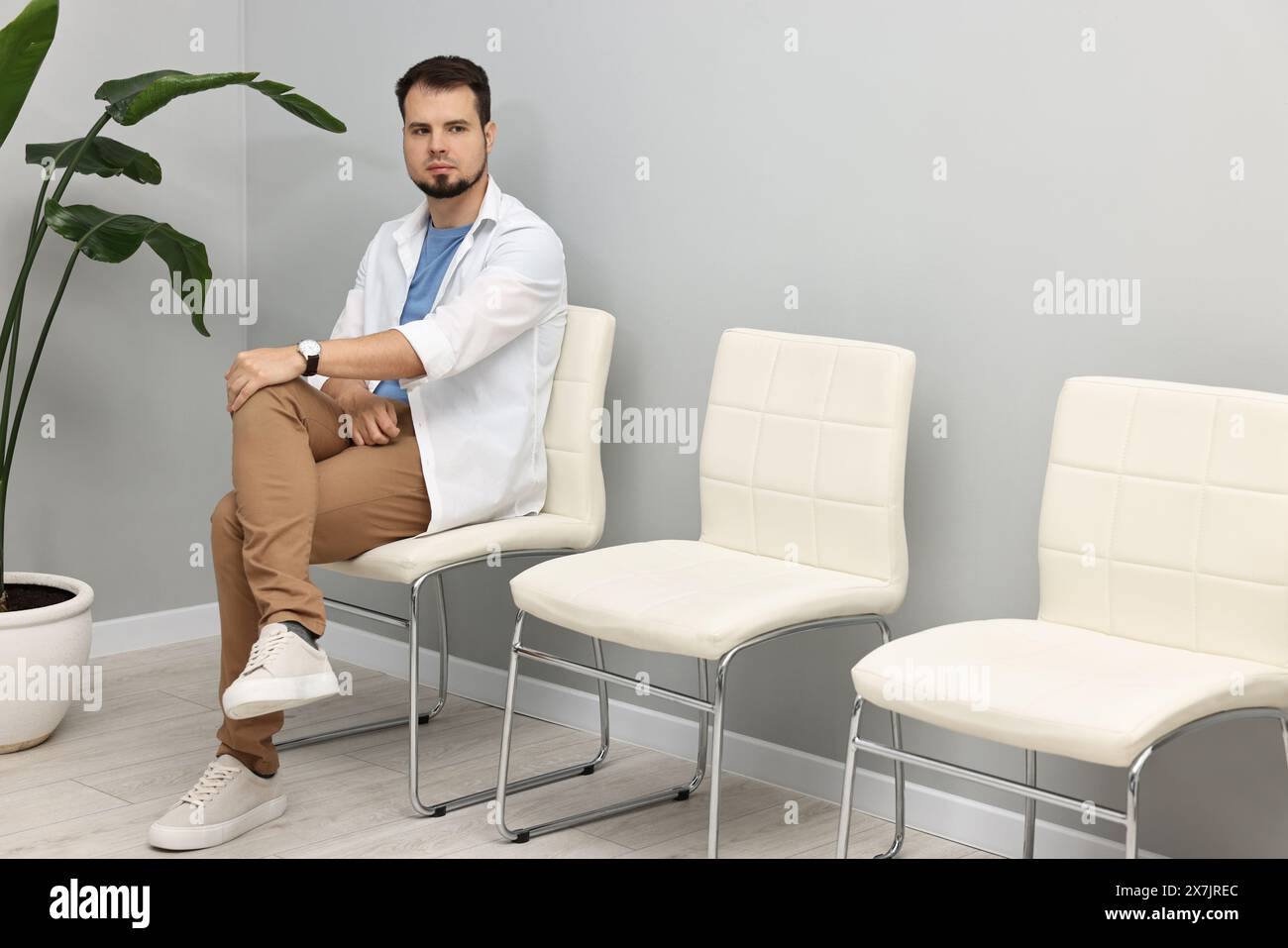 Man sitting on chair and waiting for appointment indoors Stock Photo ...