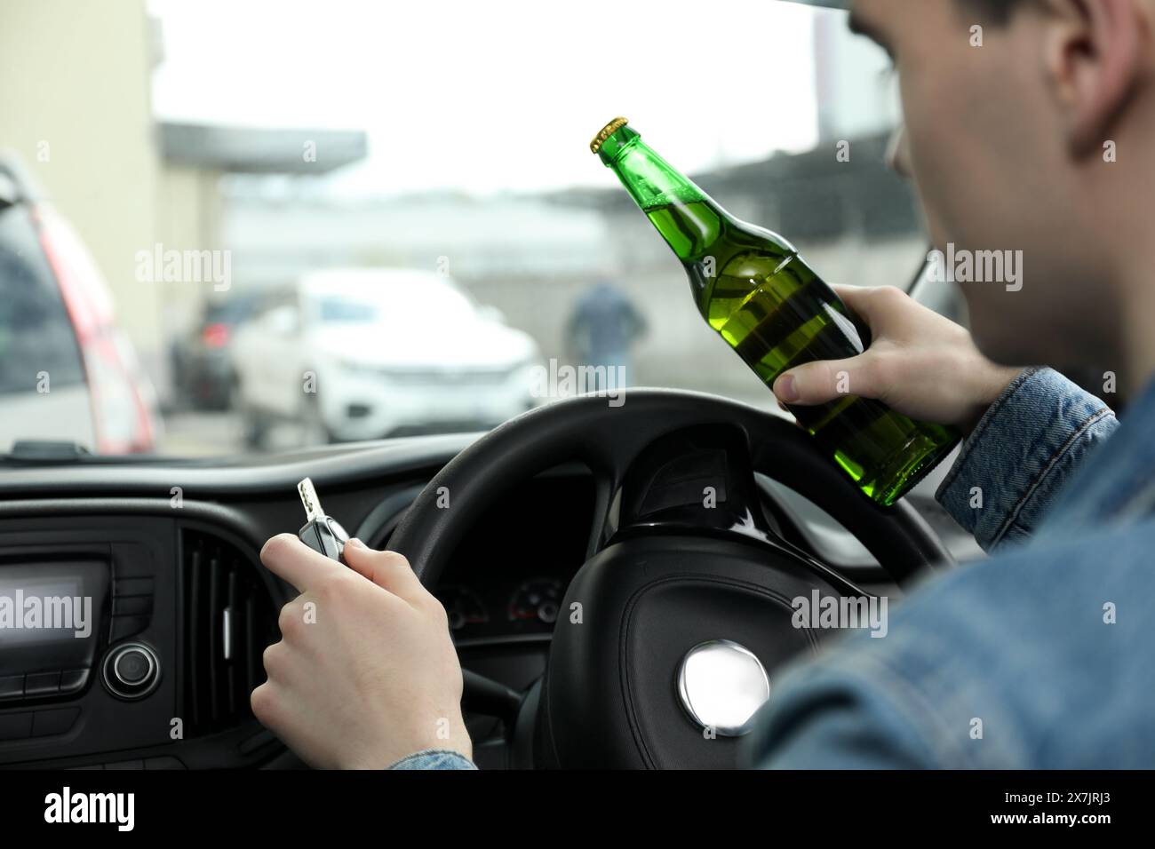 Man with bottle of beer driving car, closeup. Don't drink and drive ...