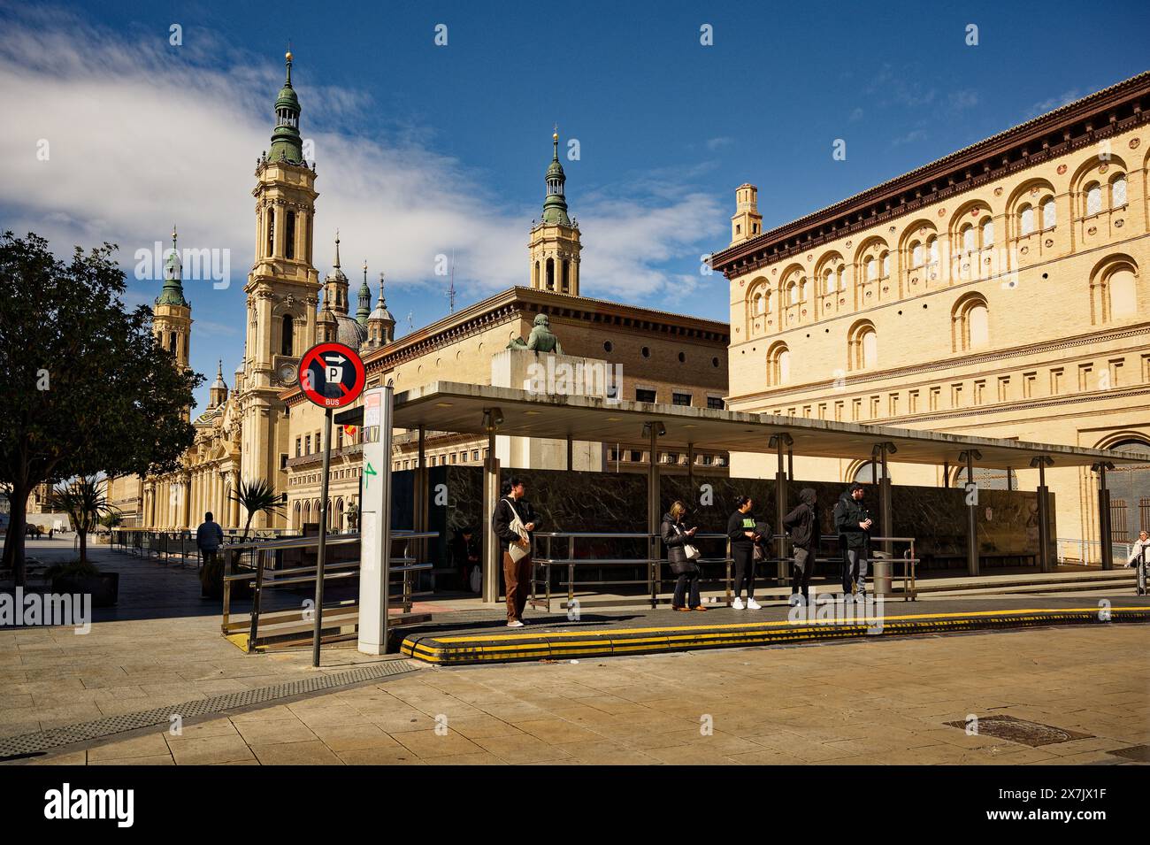 People wait on a makeshift platform at a bus stop, their attention on ...