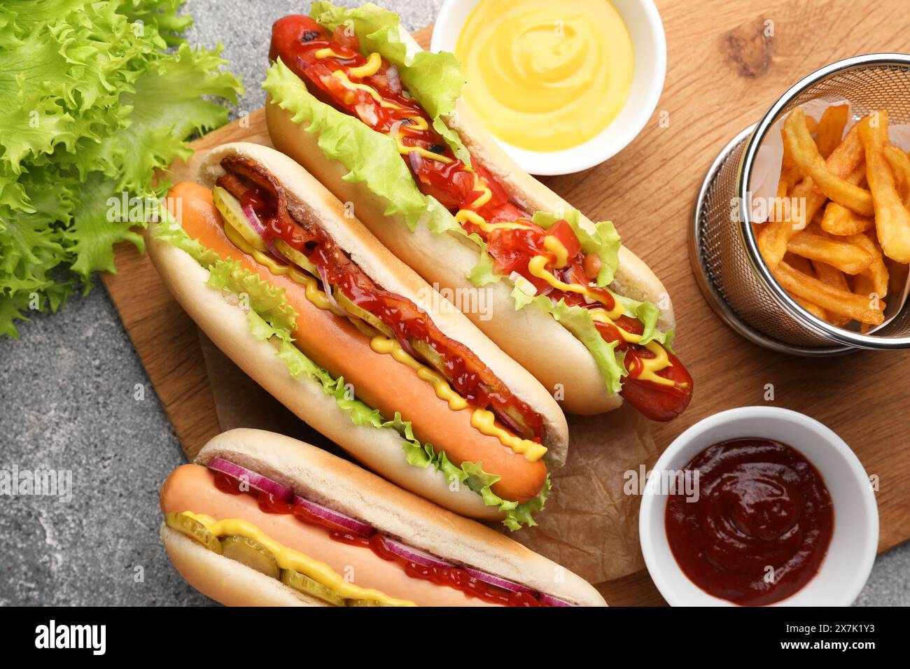 Delicious hot dogs with different toppings served on grey table, flat ...