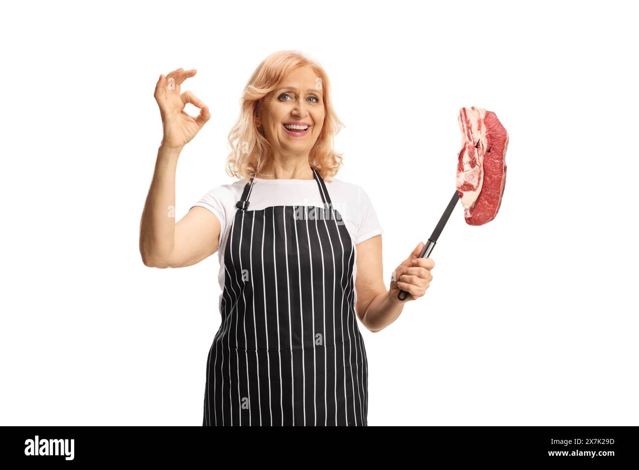 Woman holding a raw meat steak on a fork and gesturing ok sign isolated ...