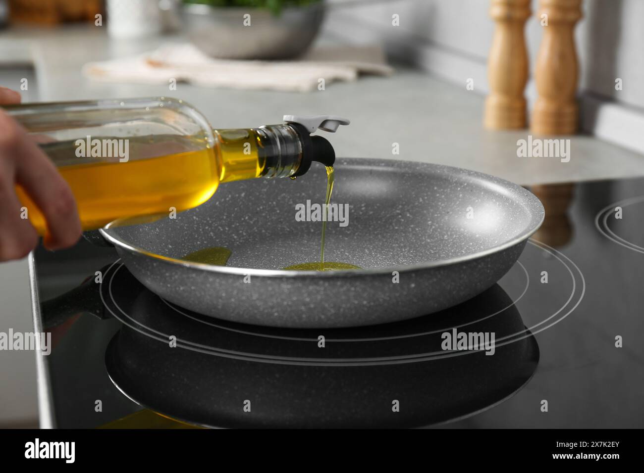 Vegetable fats. Woman pouring cooking oil into frying pan on stove in ...