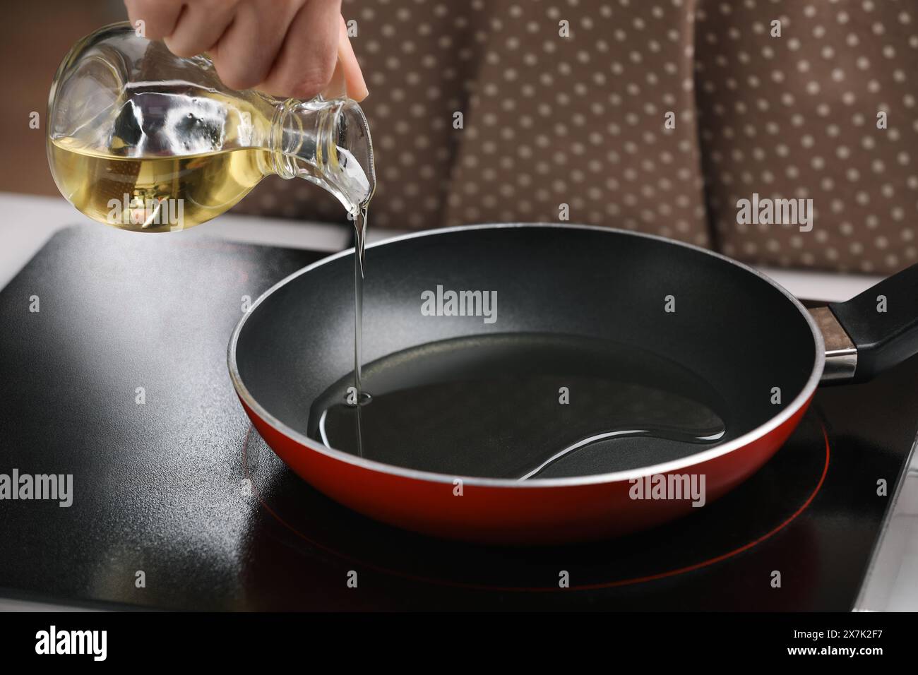 Vegetable fats. Woman pouring cooking oil into frying pan on stove ...