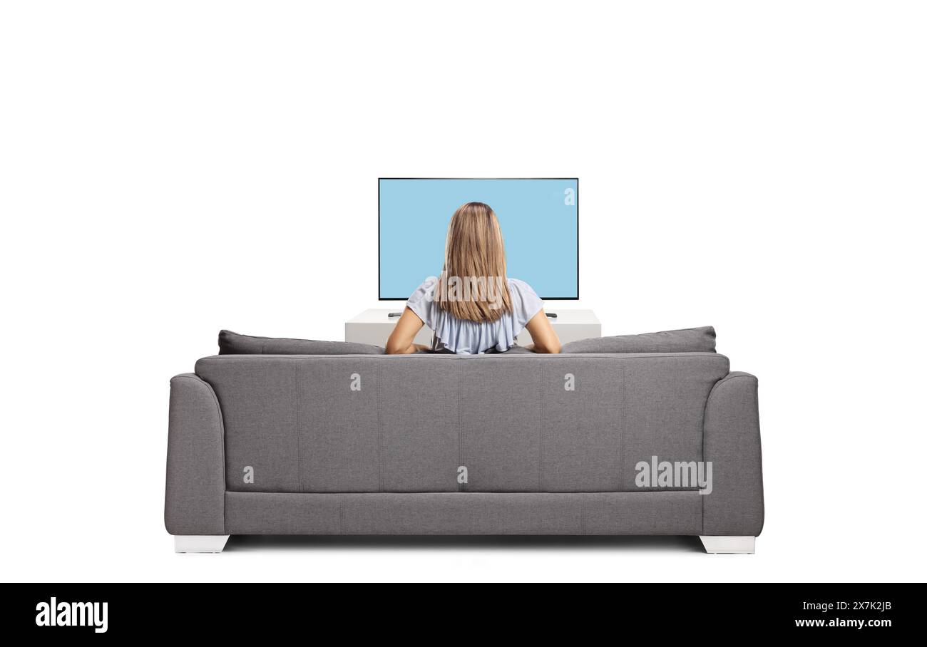 Rear view shot of a young woman sitting on a sofa and watching tv ...