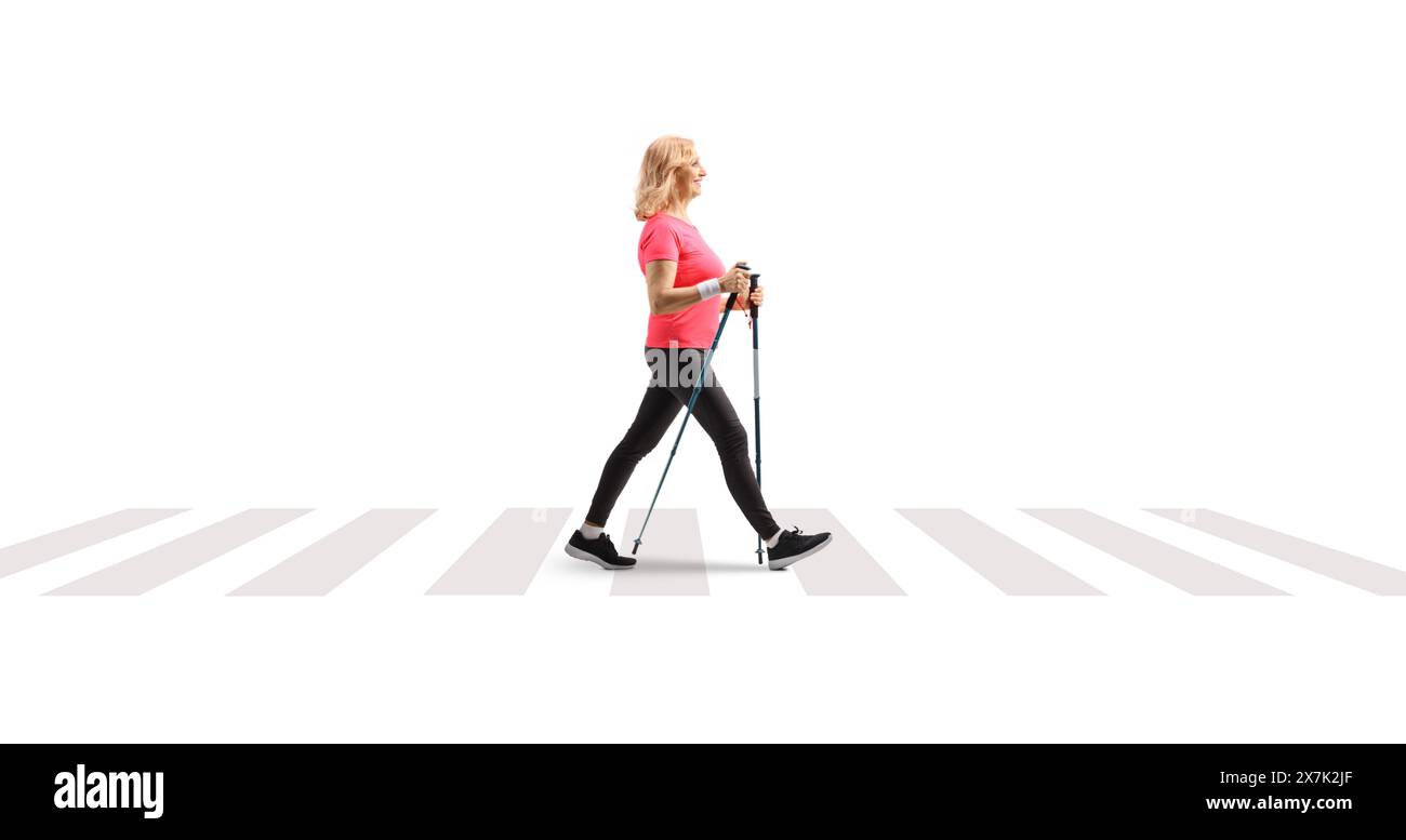 Full length profile shot of a middle aged woman walking with trekking ...