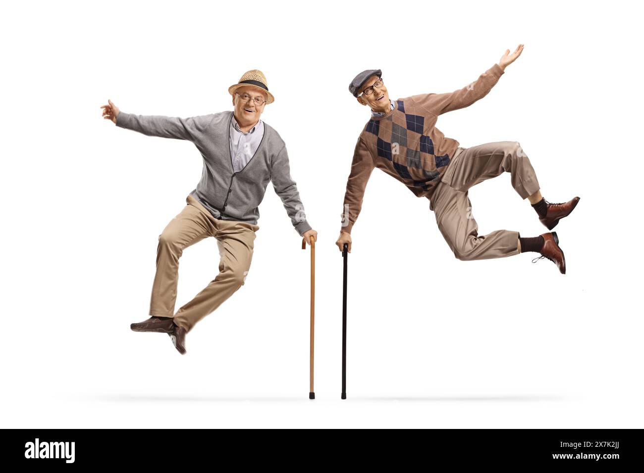 Two elderly men jumping with walking canes isolated on white background ...