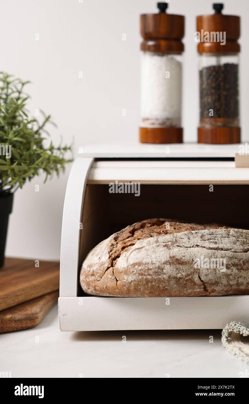 Wooden bread basket with freshly baked loaves on white marble table in ...