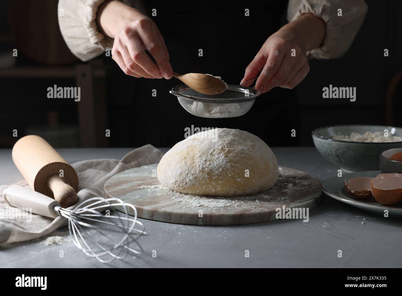 Making dough. Woman sifting flour at grey table, closeup Stock Photo ...
