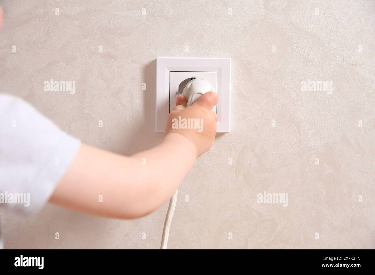Little child playing with electrical socket and plug indoors, closeup ...