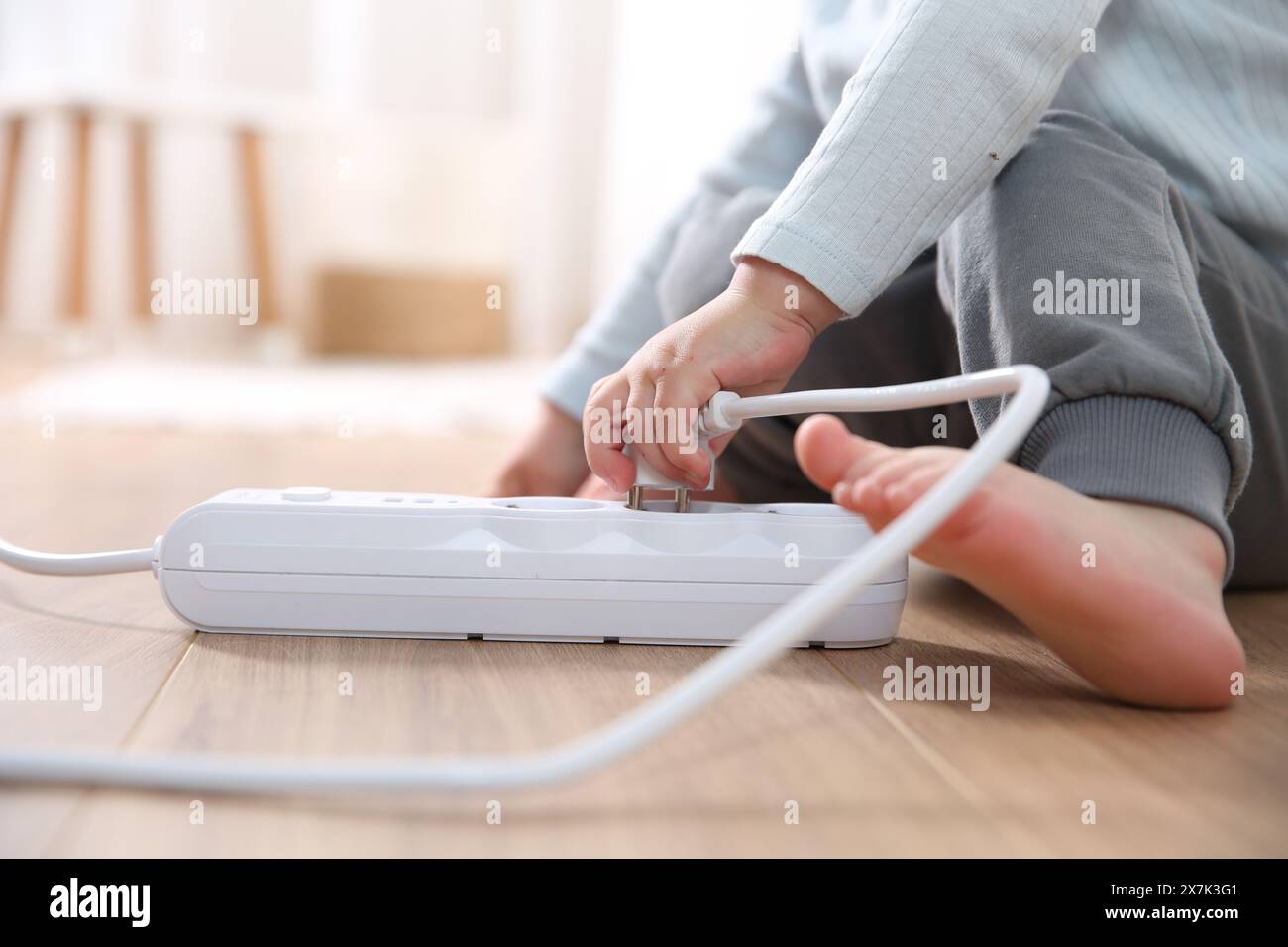 Little child playing with power strip and plug on floor indoors ...