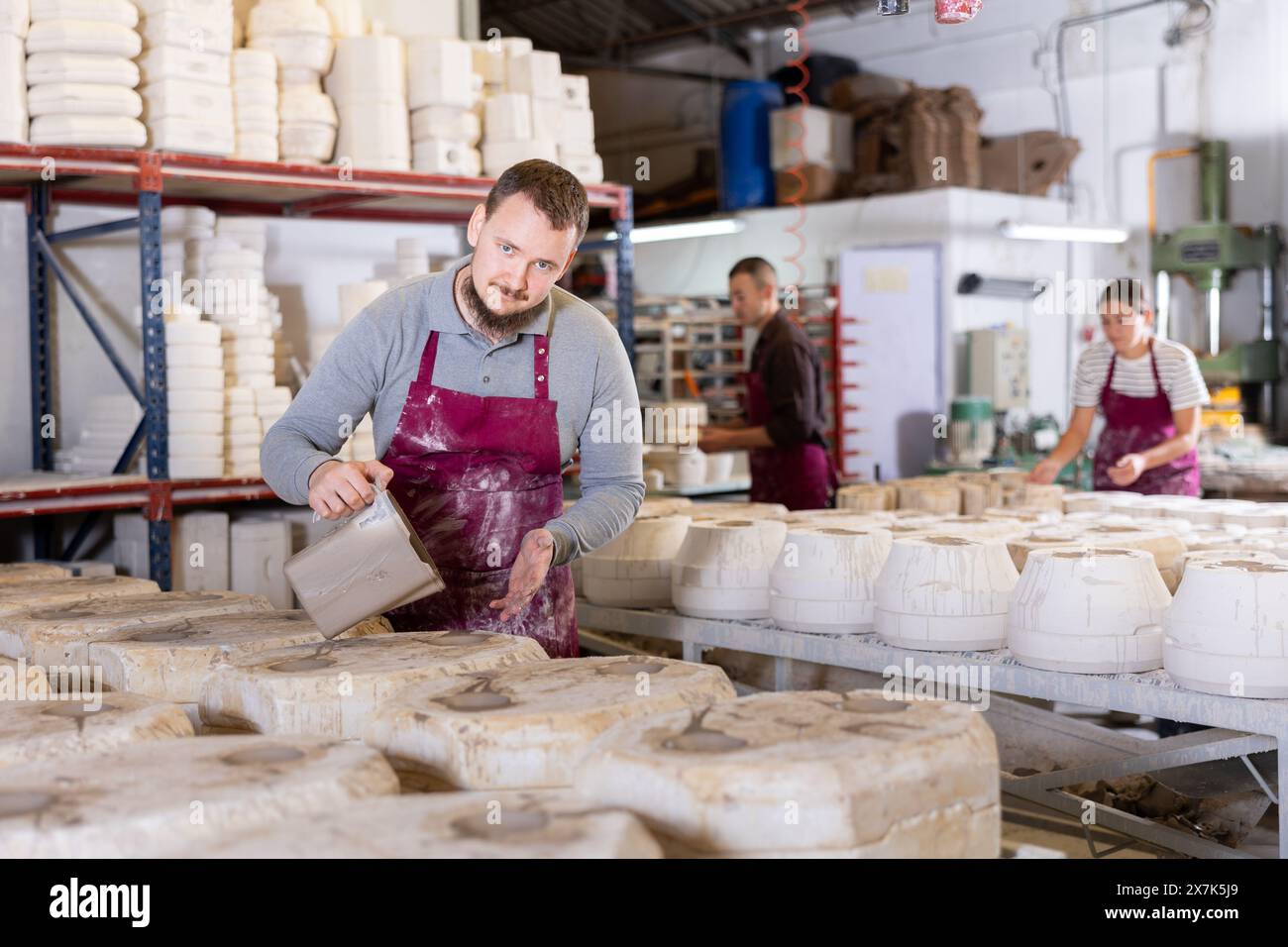 Artisan demonstrating process of pouring slip in casting molds in ...