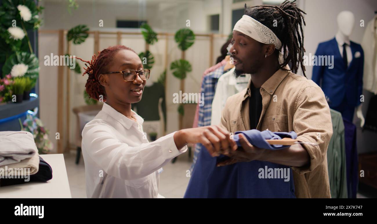 Employee assisting customer in luxury fashion boutique, helping him try ...