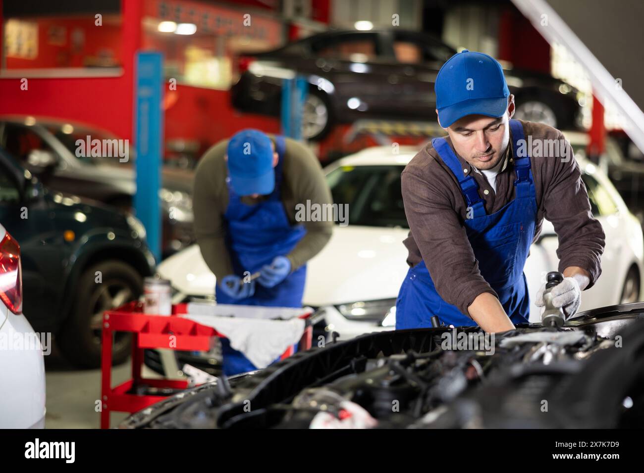 Skilled male auto mechanic in blue overalls repairing automobile Stock ...