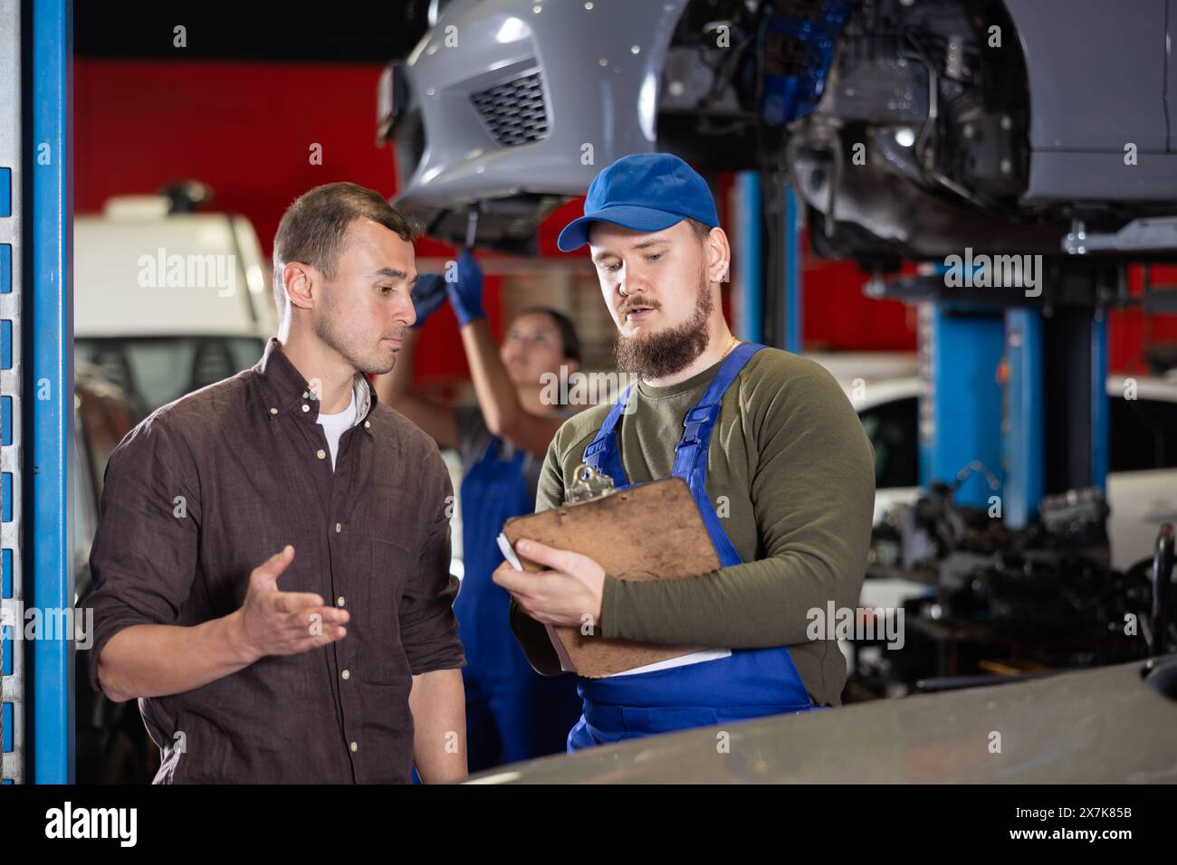 Mechanic guy signs agreement with young man client Stock Photo - Alamy