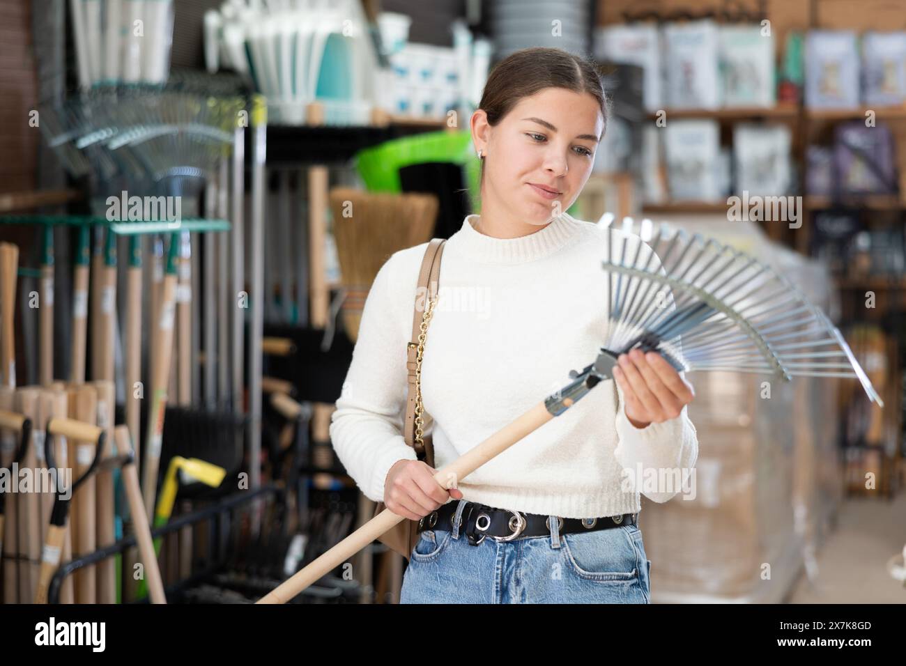 Girl carefully chooses rake in hardware store to clean garden Stock ...