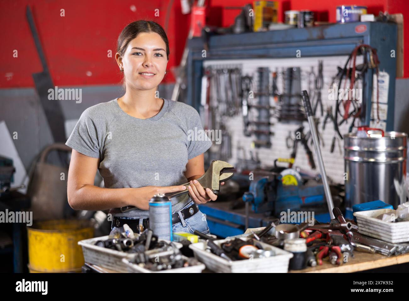 Portrait of positive girl auto mechanic with tools in her hands in car ...