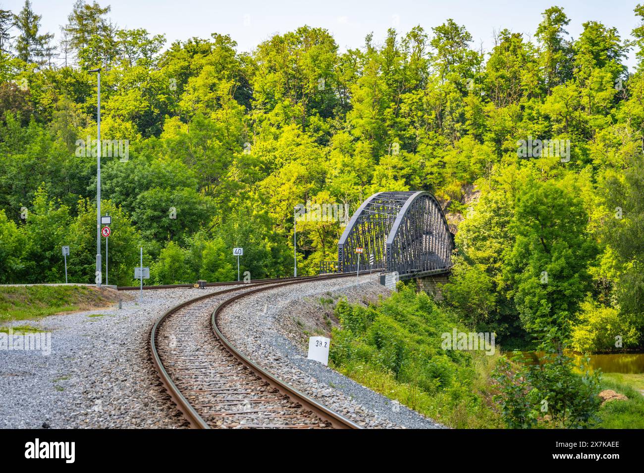 A curved railway bridge in Rataje surrounded by dense greenery and ...