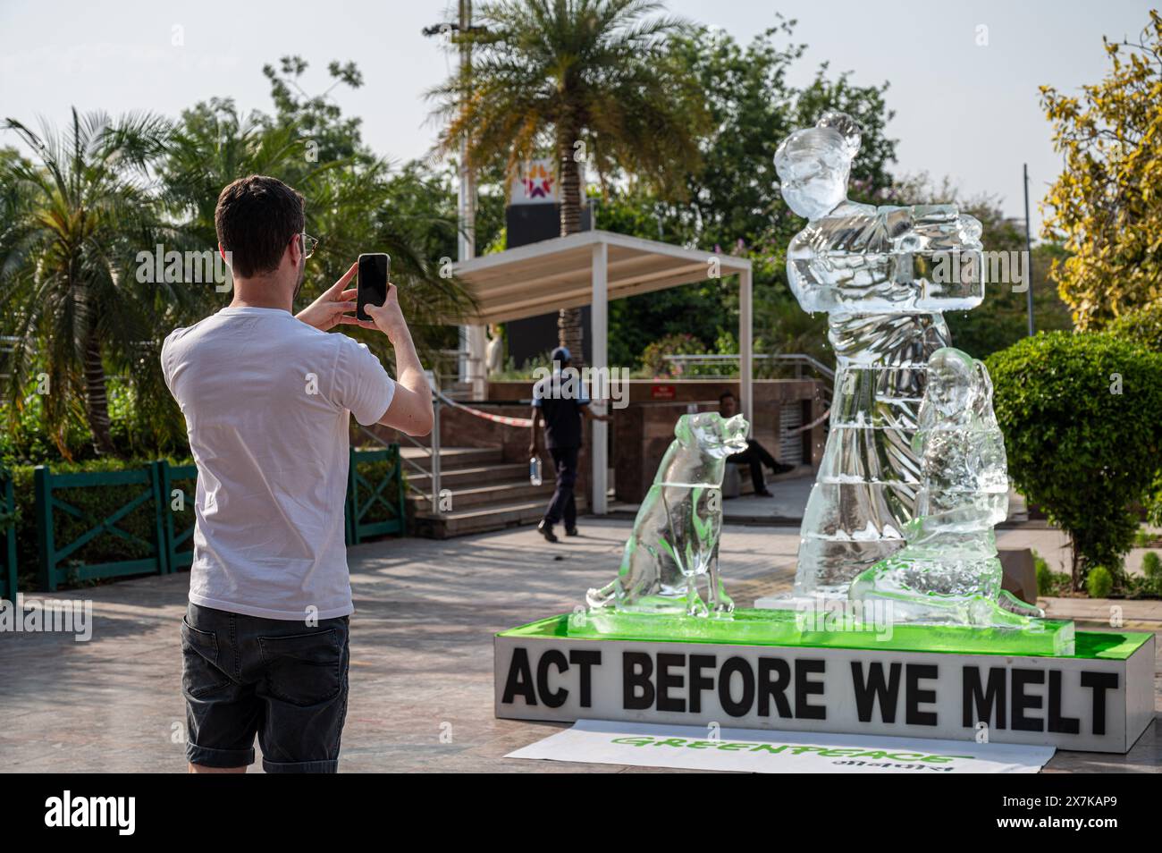 A visitor takes a photo of the ice sculpture, melting under the ...