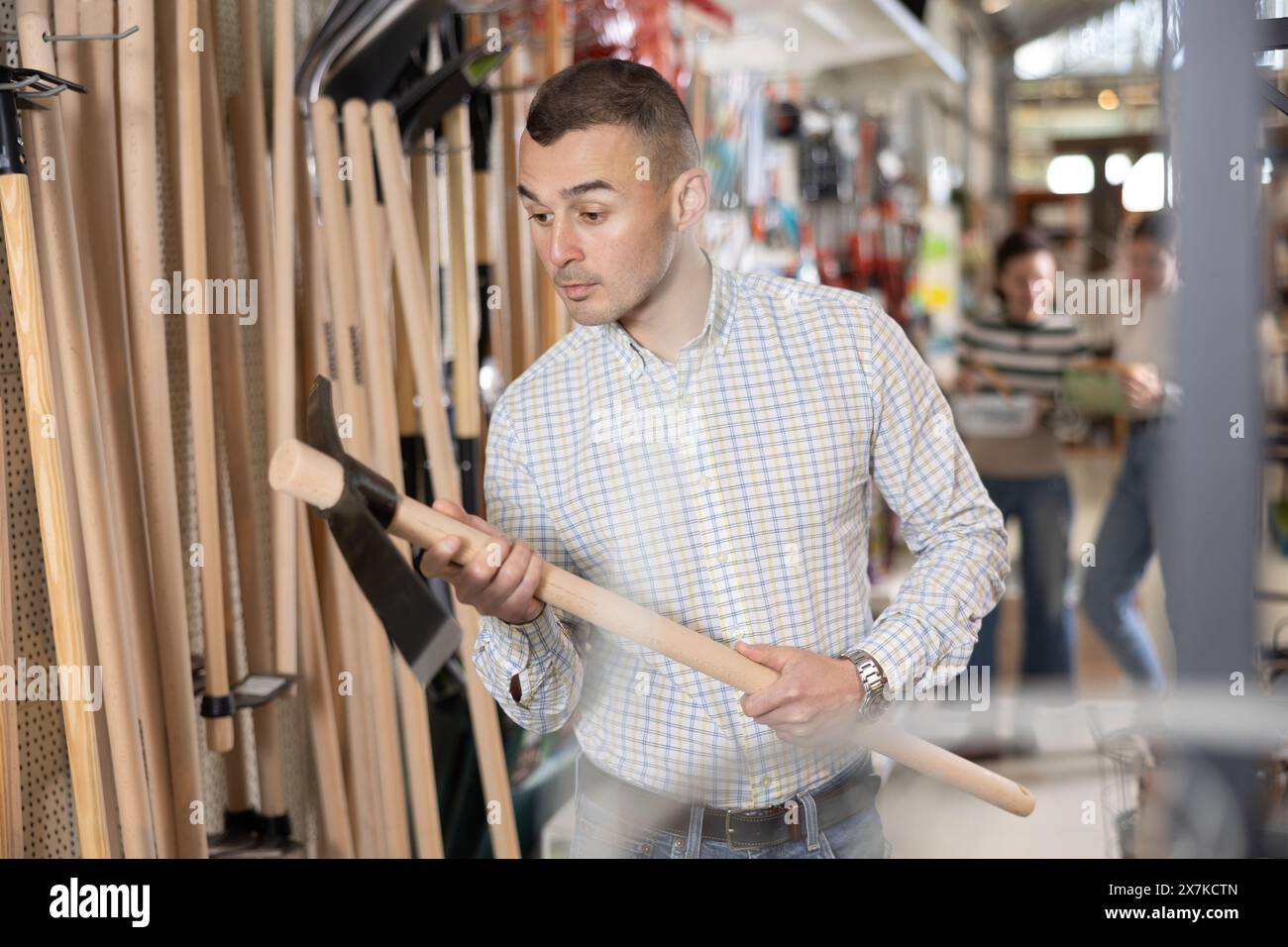 Buying pickaxe in supermarket - man with interest chooses pickaxe in ...