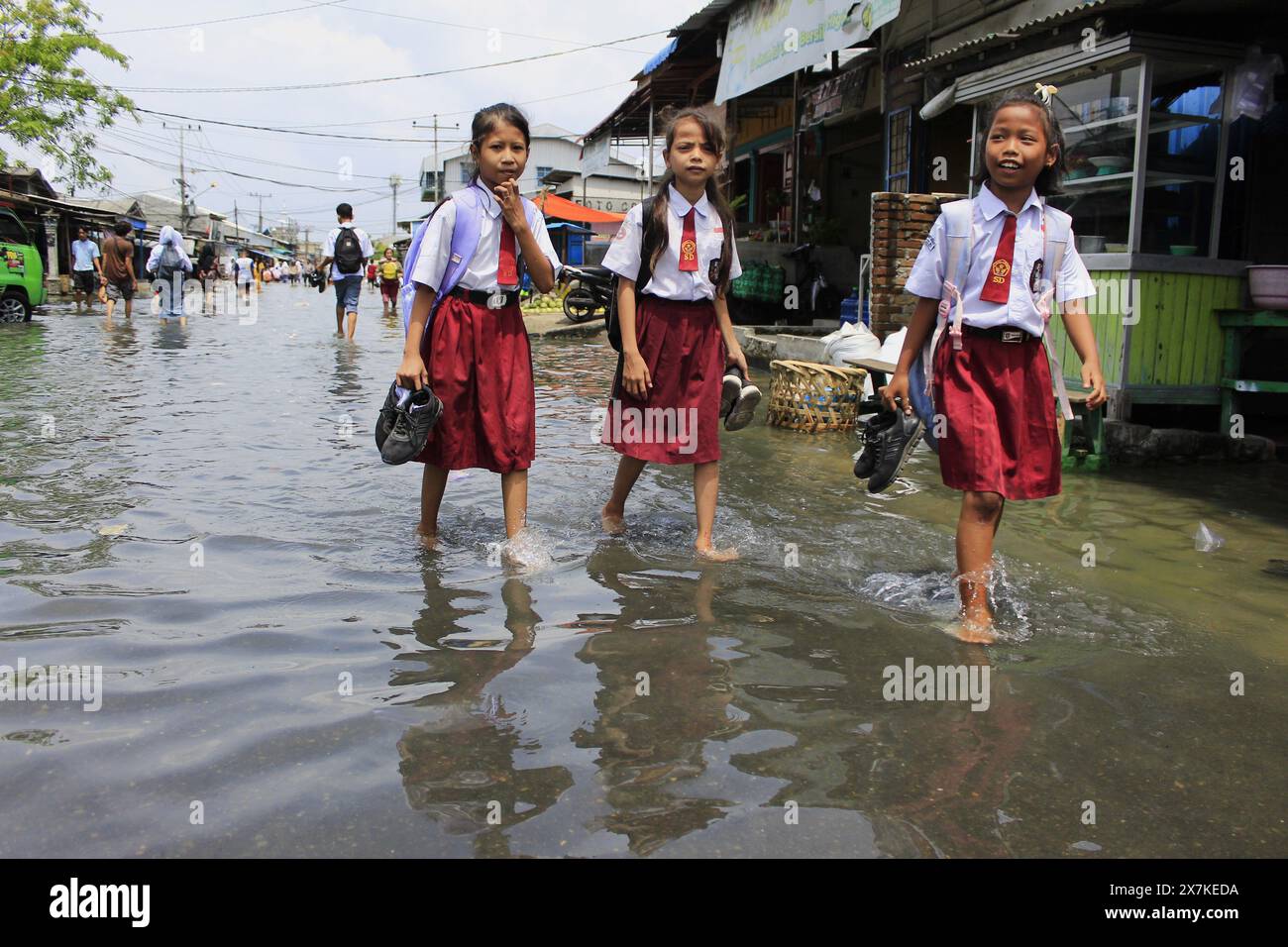 Medan Selayangh, North Sumatra, Indonesia. 20th May, 2024. Three school girls wade through ...