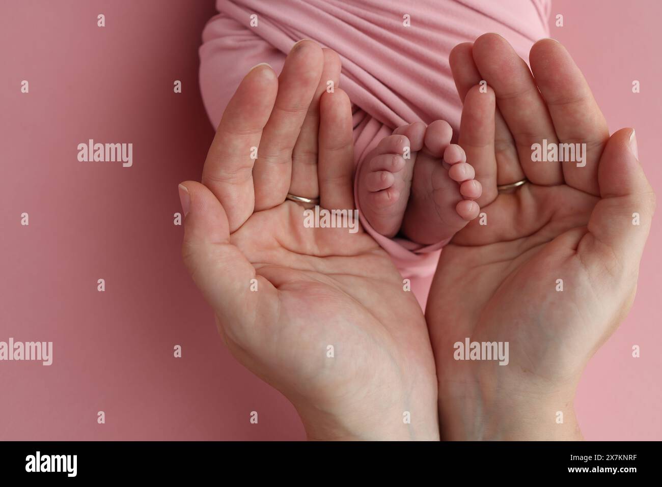 The palms of the father, the mother are holding the foot of the newborn ...