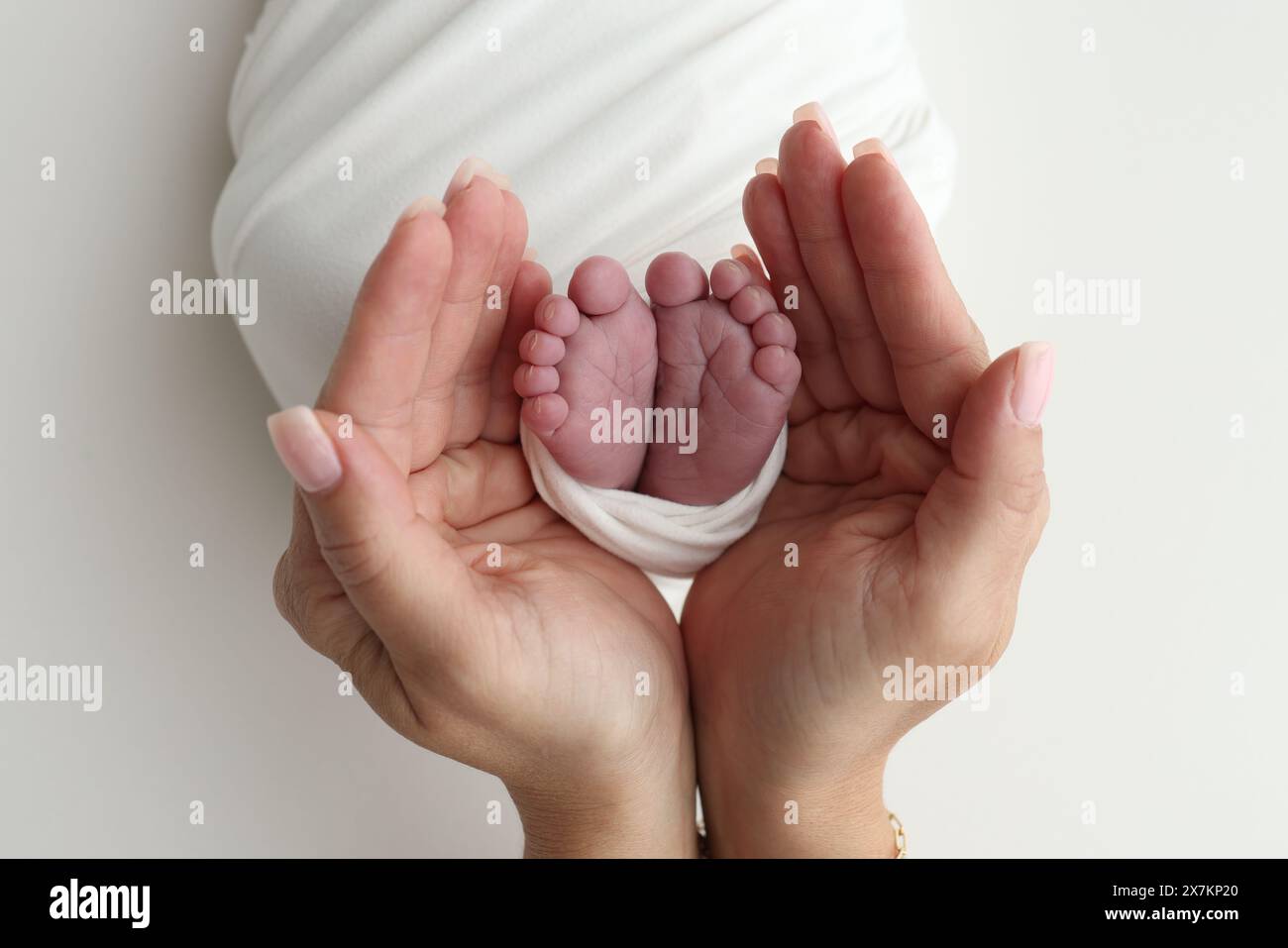 The palms of the father, the mother are holding the foot of the newborn ...