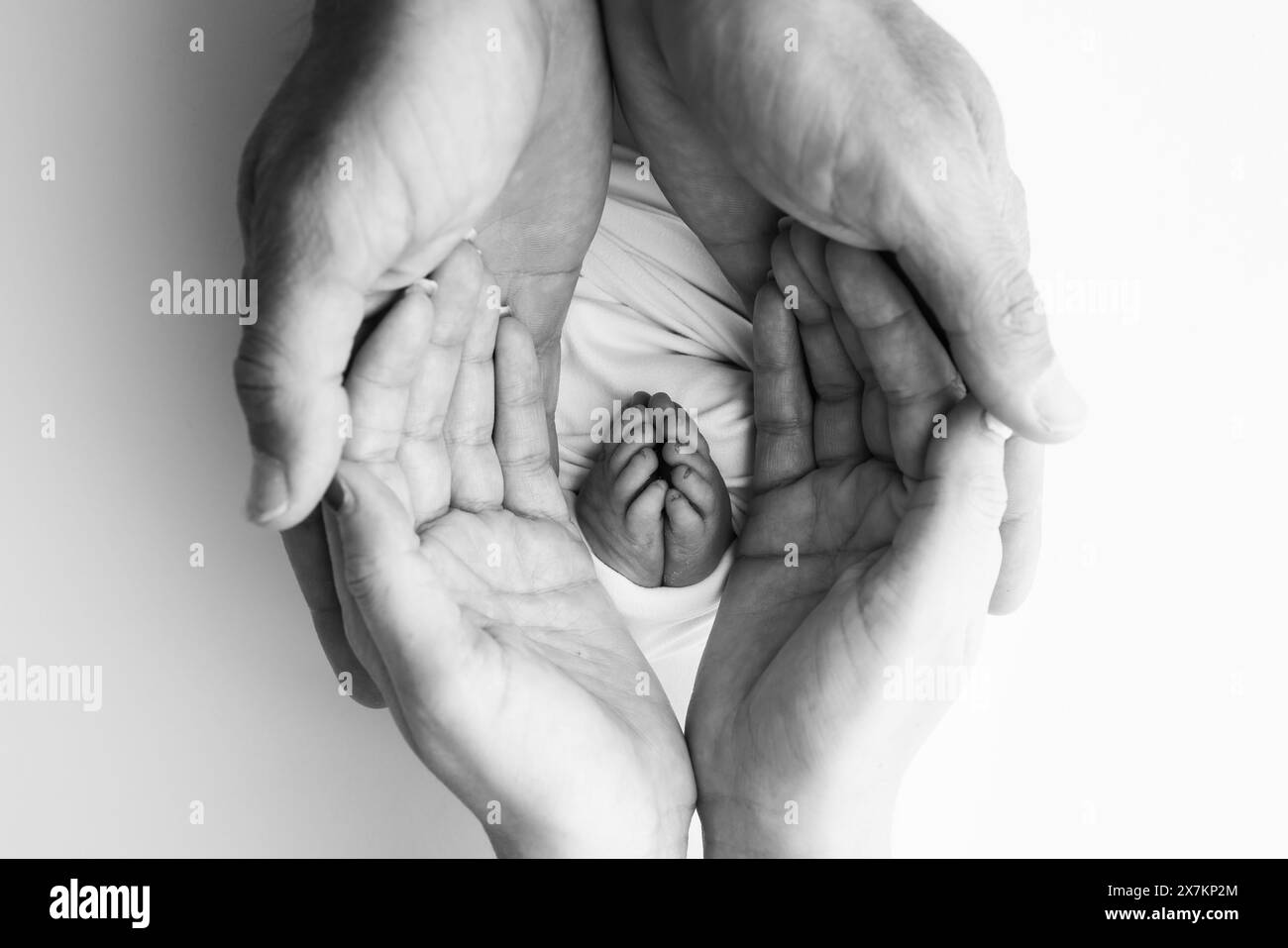 The palms of the father, the mother are holding the foot of the newborn ...