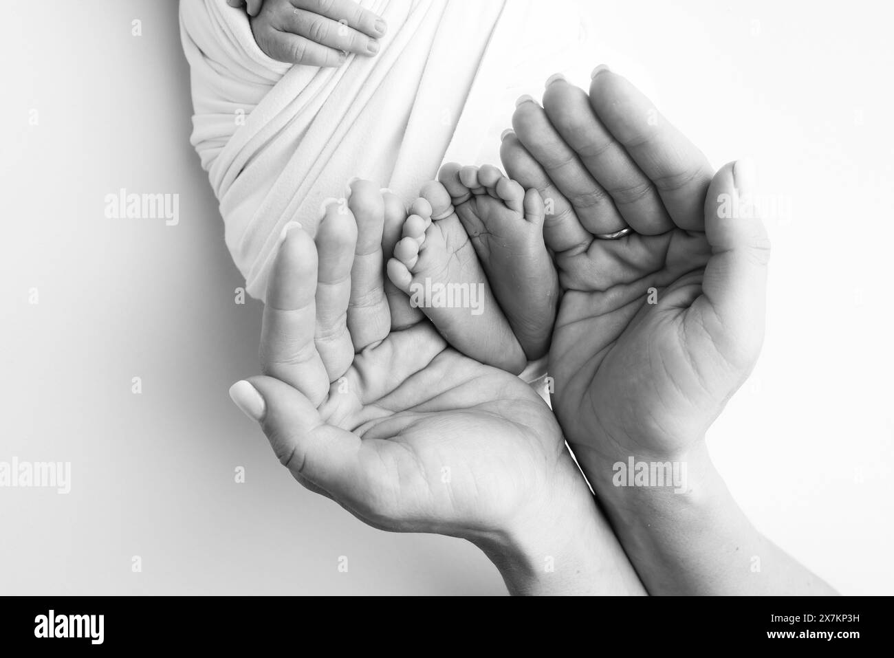The palms of the father, the mother are holding the foot of the newborn ...