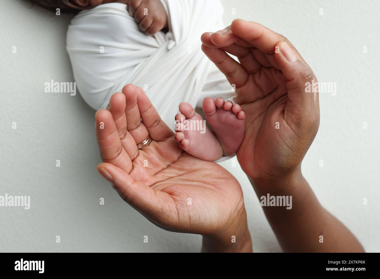 The palms of the father, the mother are holding the foot of the newborn ...