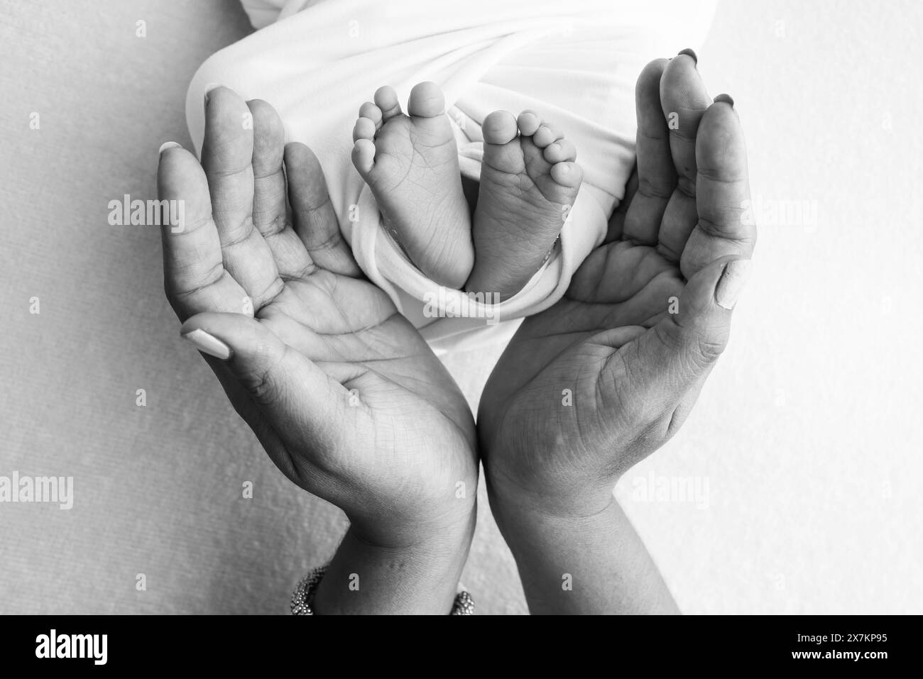 The palms of the father, the mother are holding the foot of the newborn ...